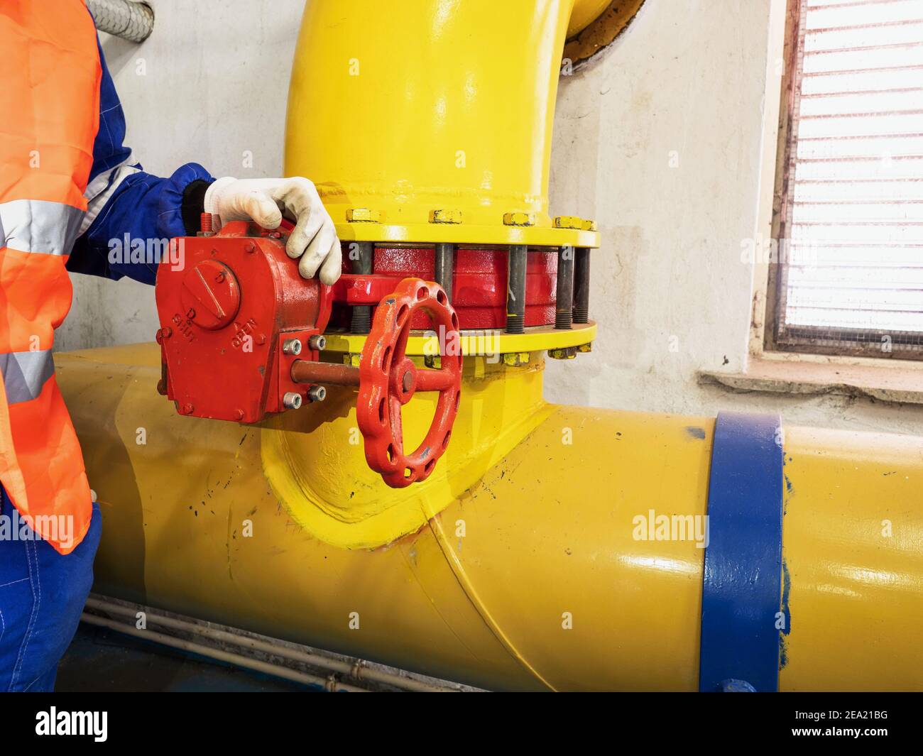 Worker turning wheel of valve in industrial factory. Employee dressed ...
