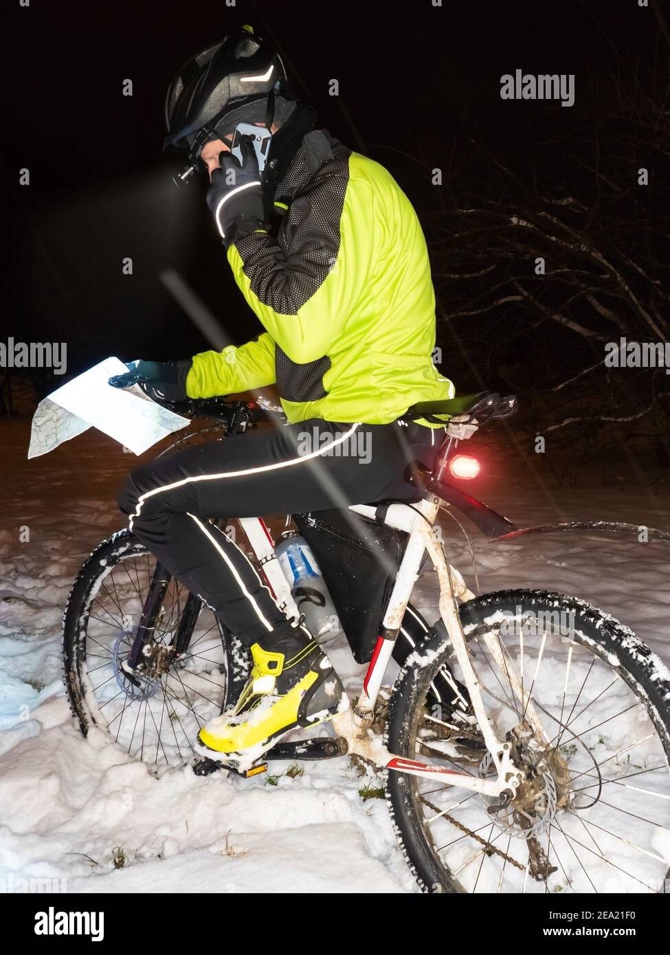 Biker over the map with the race route calling a friend. Extreme night ...