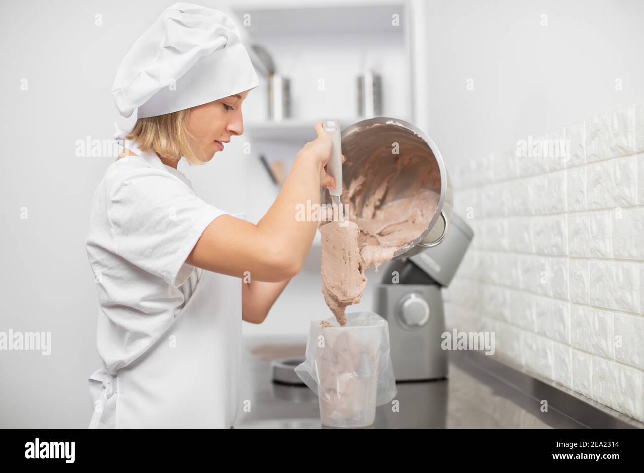 Pretty young woman chef pouring macaron dough, batter or cream from ...