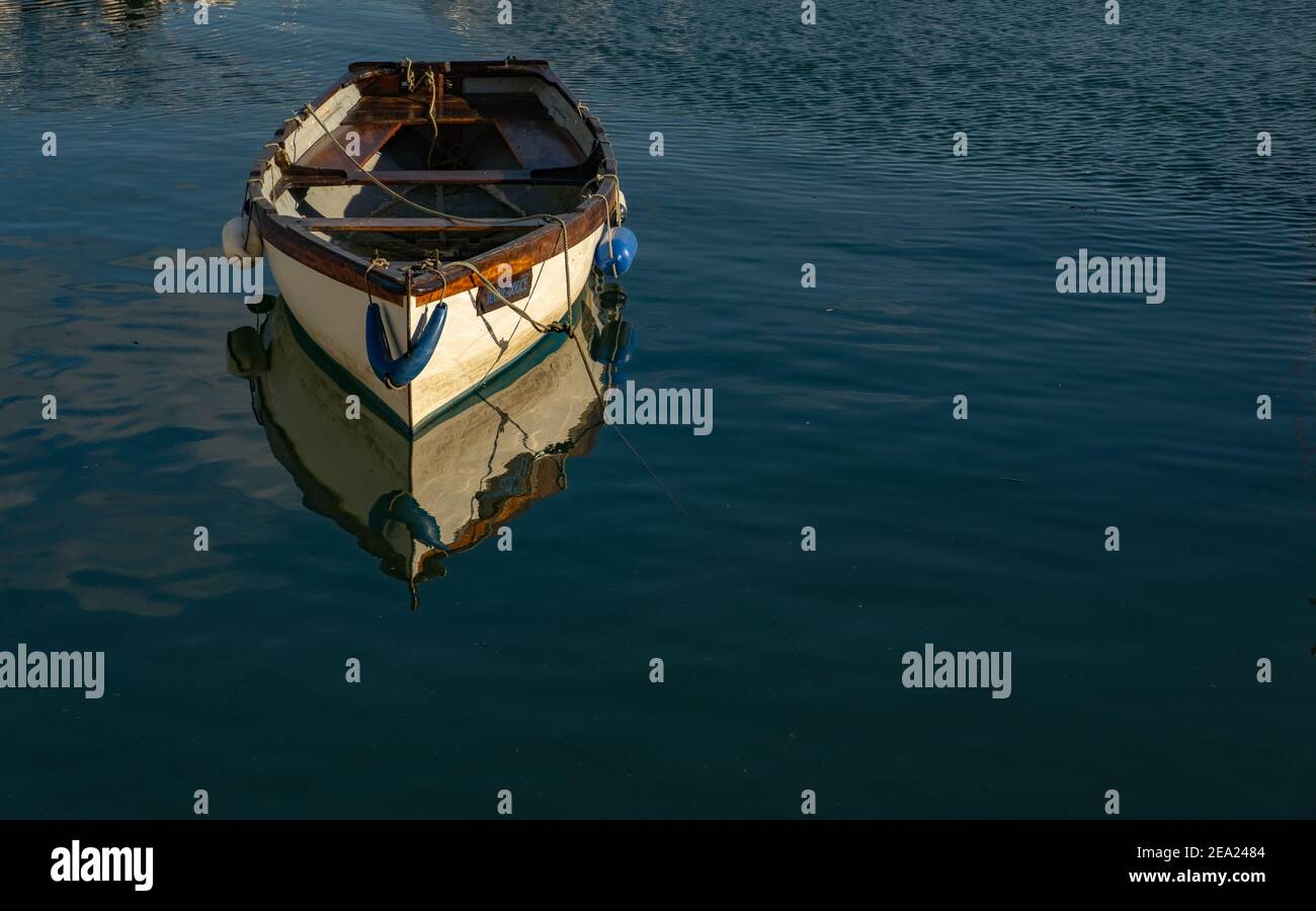 Traditional wooden, clinker rowing boat floating on still harbour ...