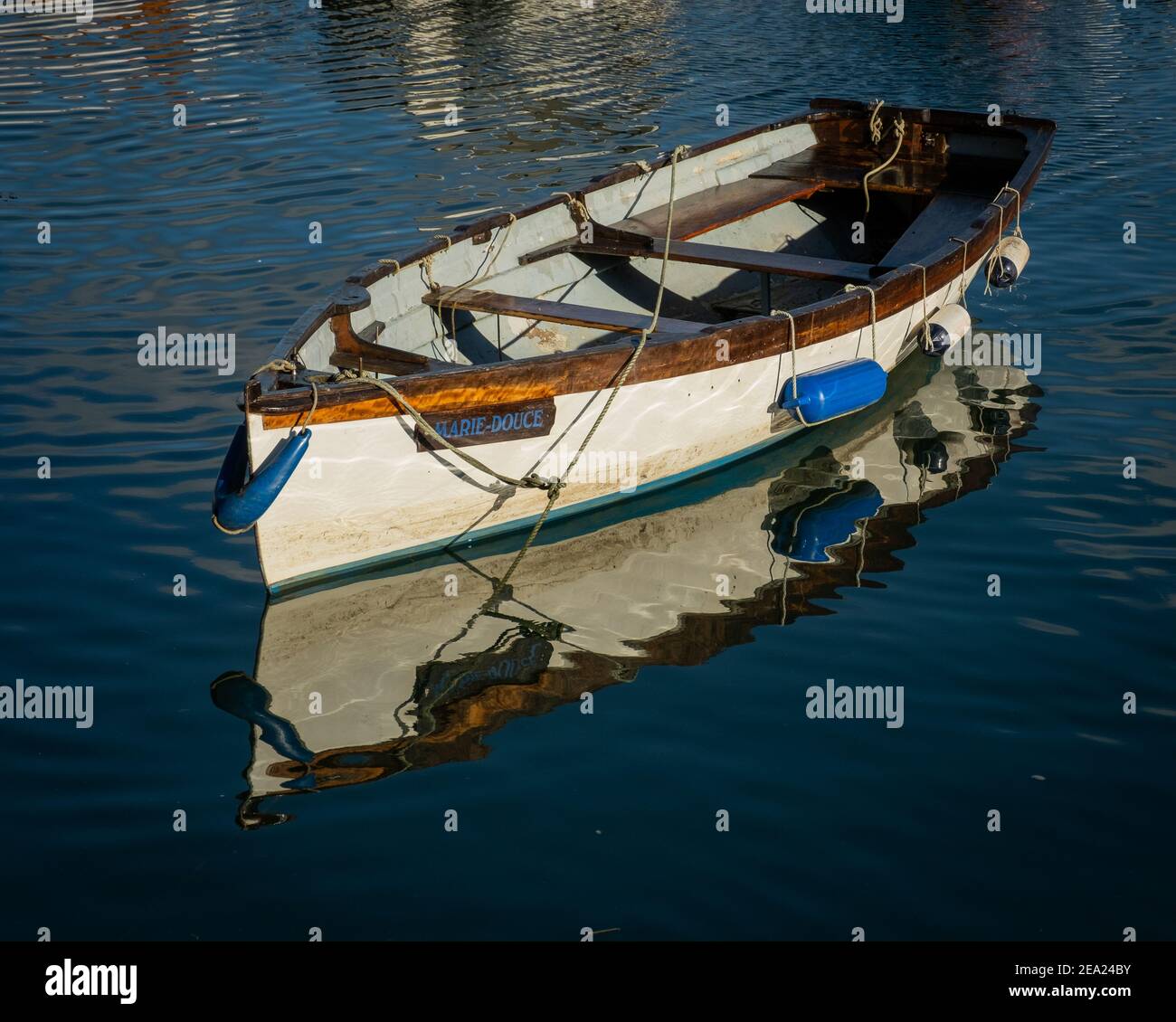 Traditional wooden, clinker rowing boat floating on still harbour ...