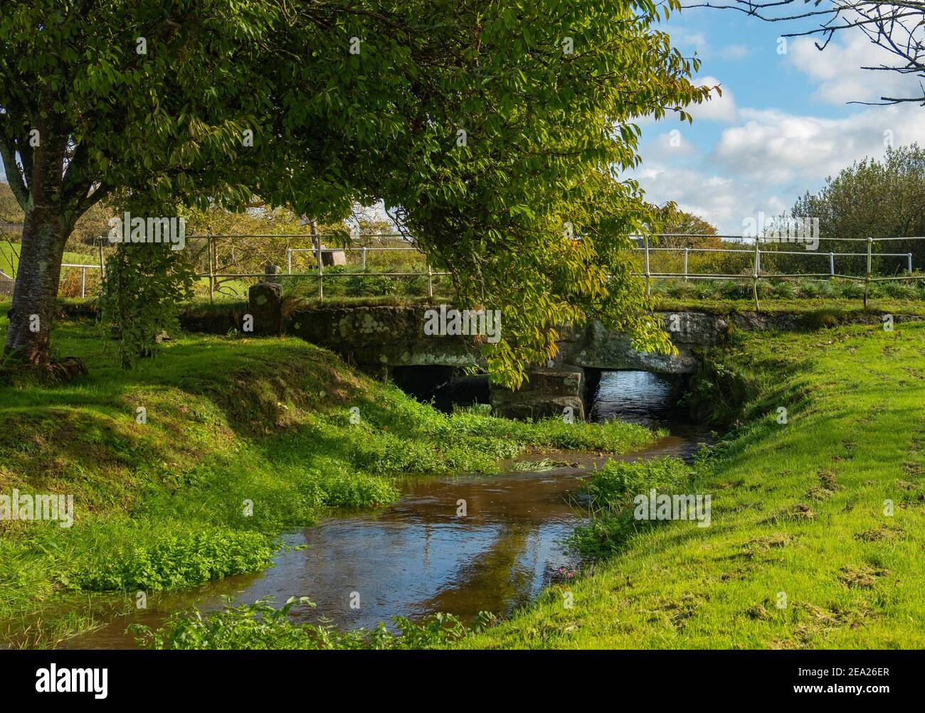 Brightly sunlit, peaceful country scene of a small river flowing under ...