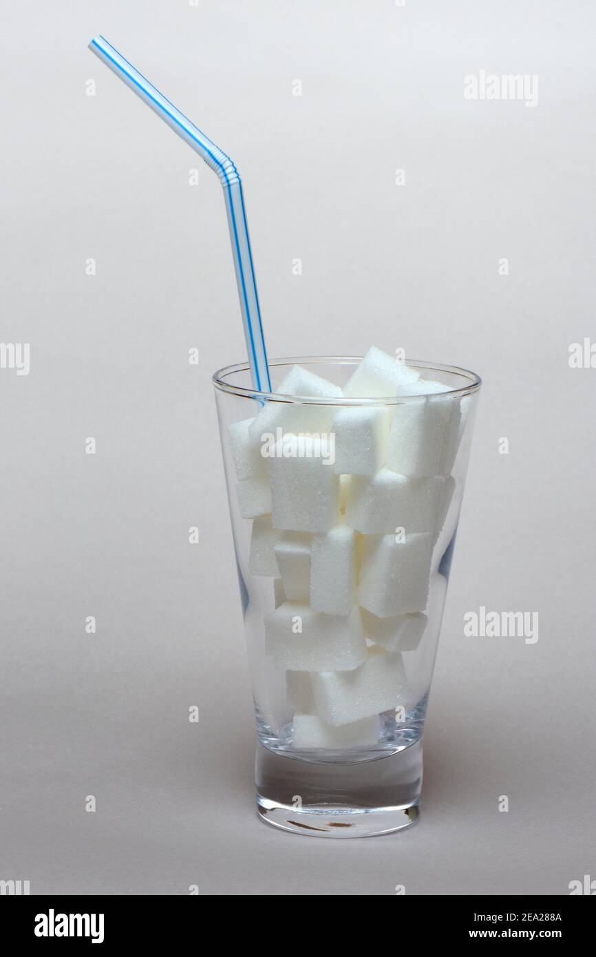 Sugar cubes in drinking glass with straw, sugar consumption, white ...