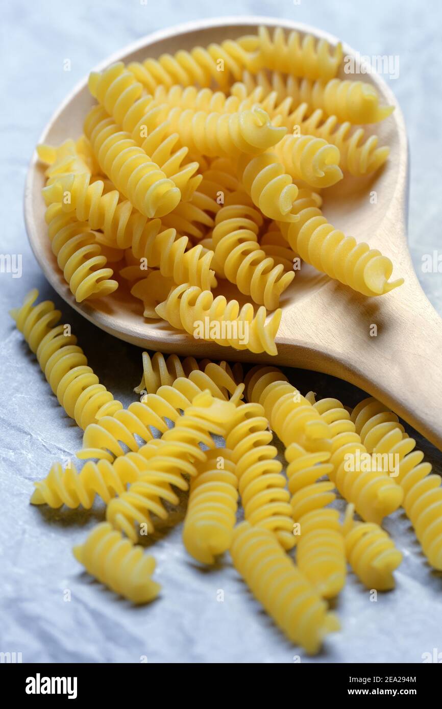 Spiral noodles in wooden ladle, Fusilli, uncooked Stock Photo - Alamy