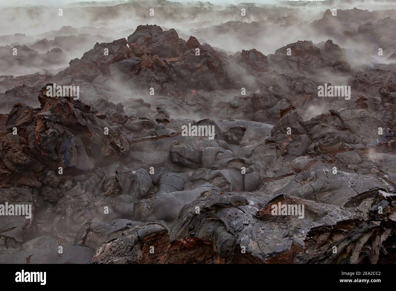 The frozen lava of the volcano during the rain evaporates foggy haze ...