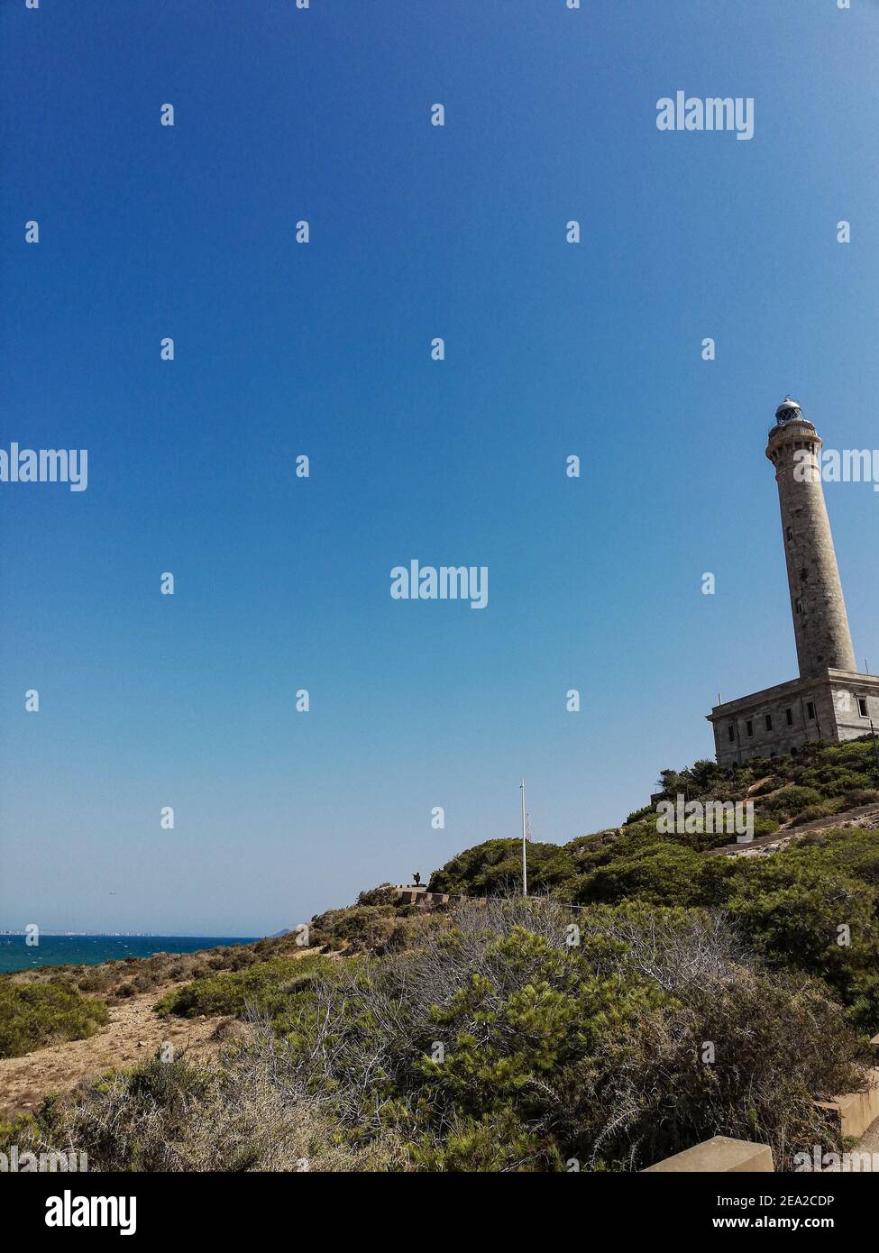 A vertical low angle shot of a lighthouse on top of a cliff under a ...