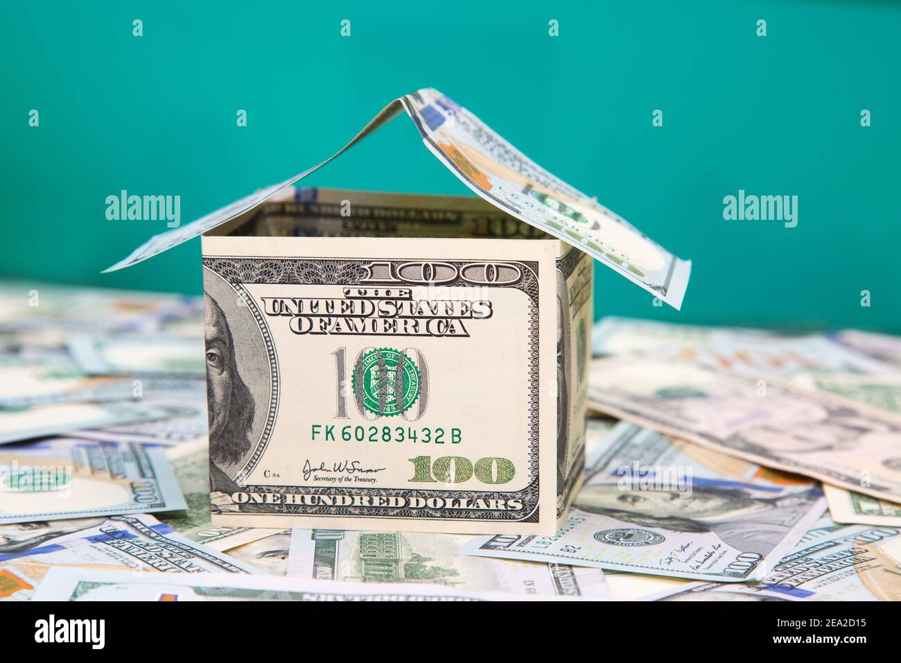House made of dollars banknotes on a green background and a heap of ...