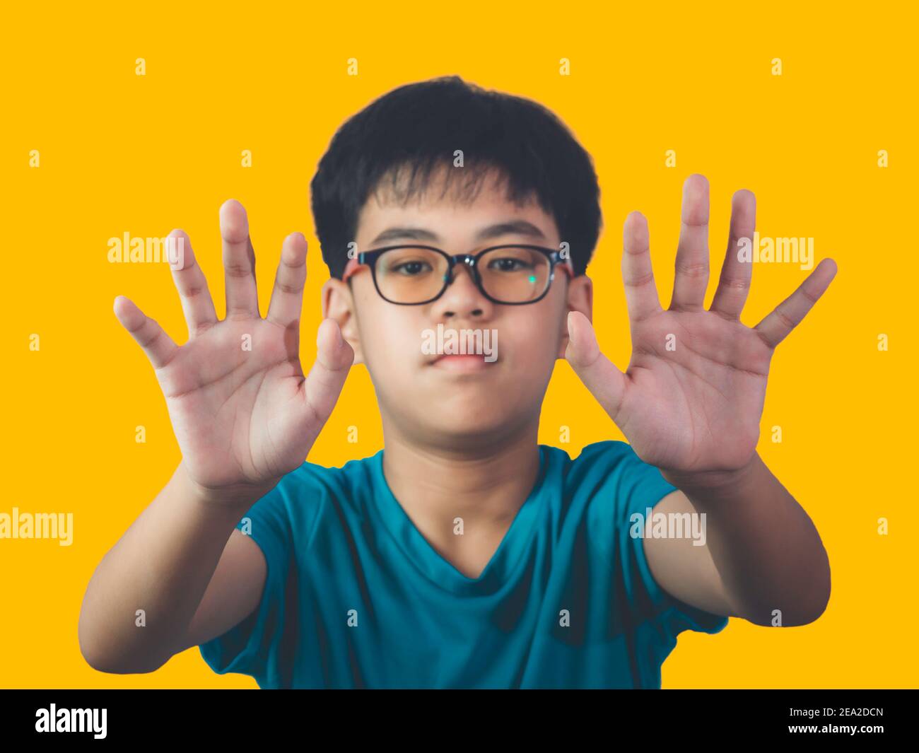 Asian boy doing stop sign with palm on yellow background. And standing ...