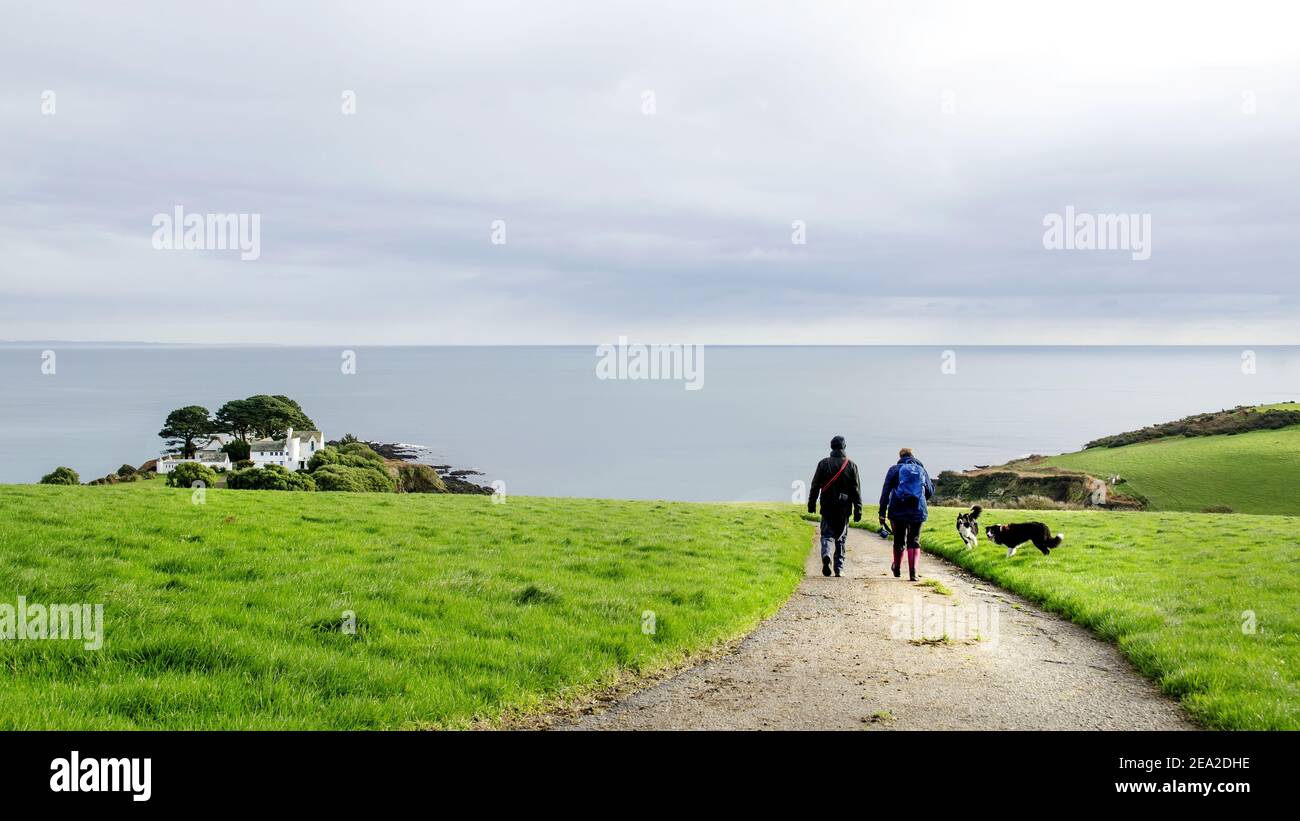 Two friends walking on Cornwall seaside Stock Photo - Alamy