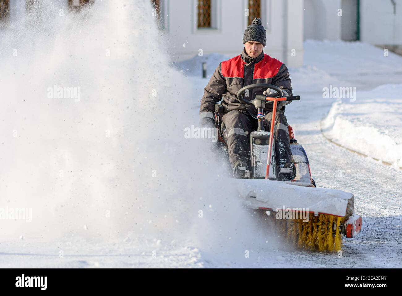 Snow-removal work with rotating brush. Man with sweeping machine ...