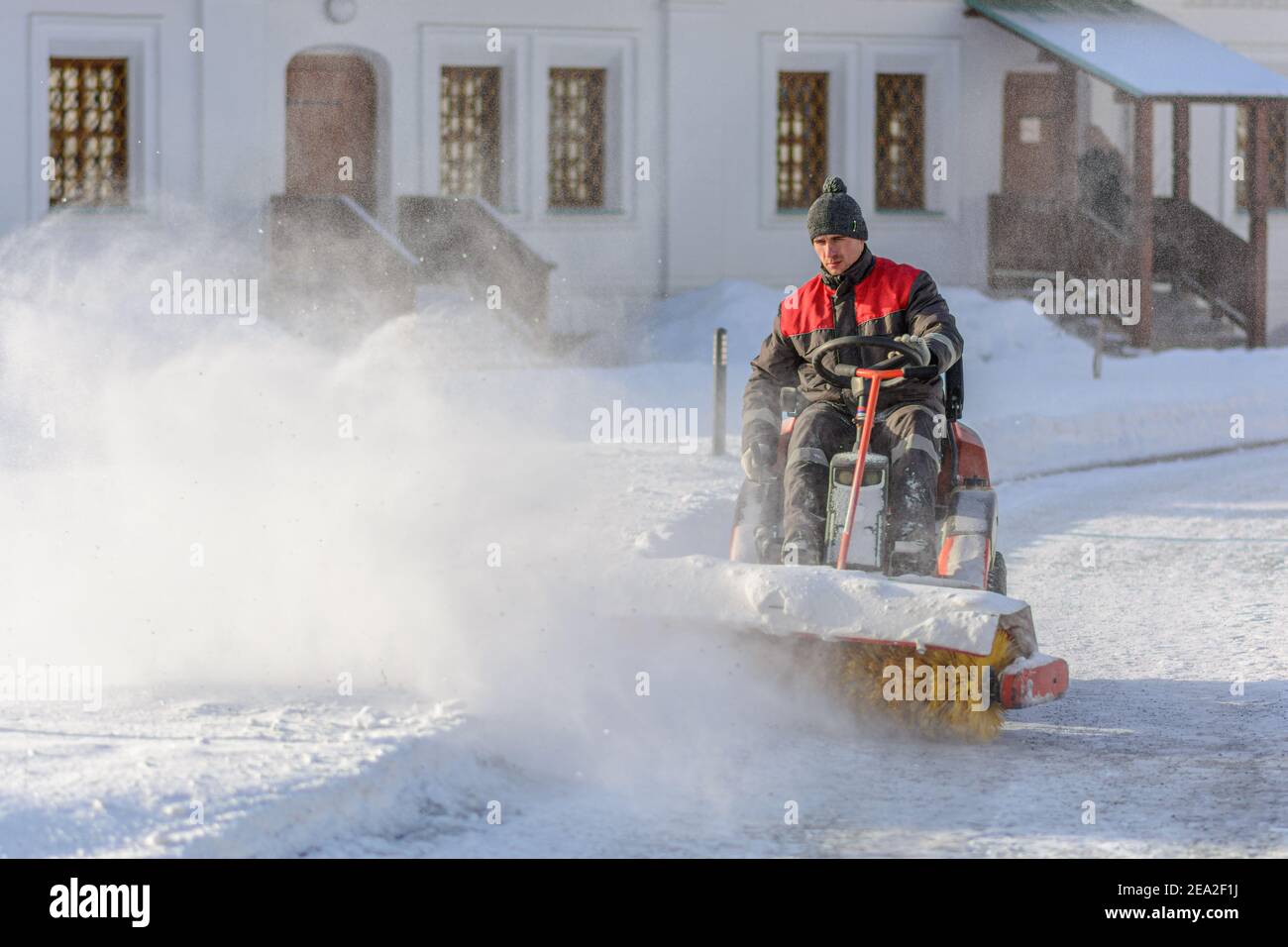 Snow-removal work with rotating brush. Man with sweeping machine ...