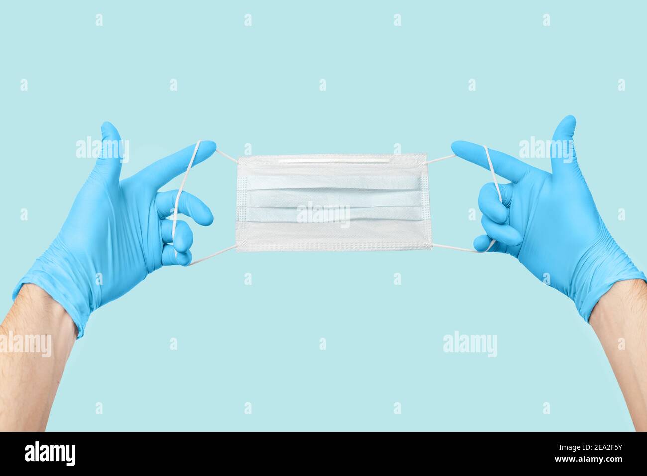Medical face mask with hands in gloves, isolated on blue background ...