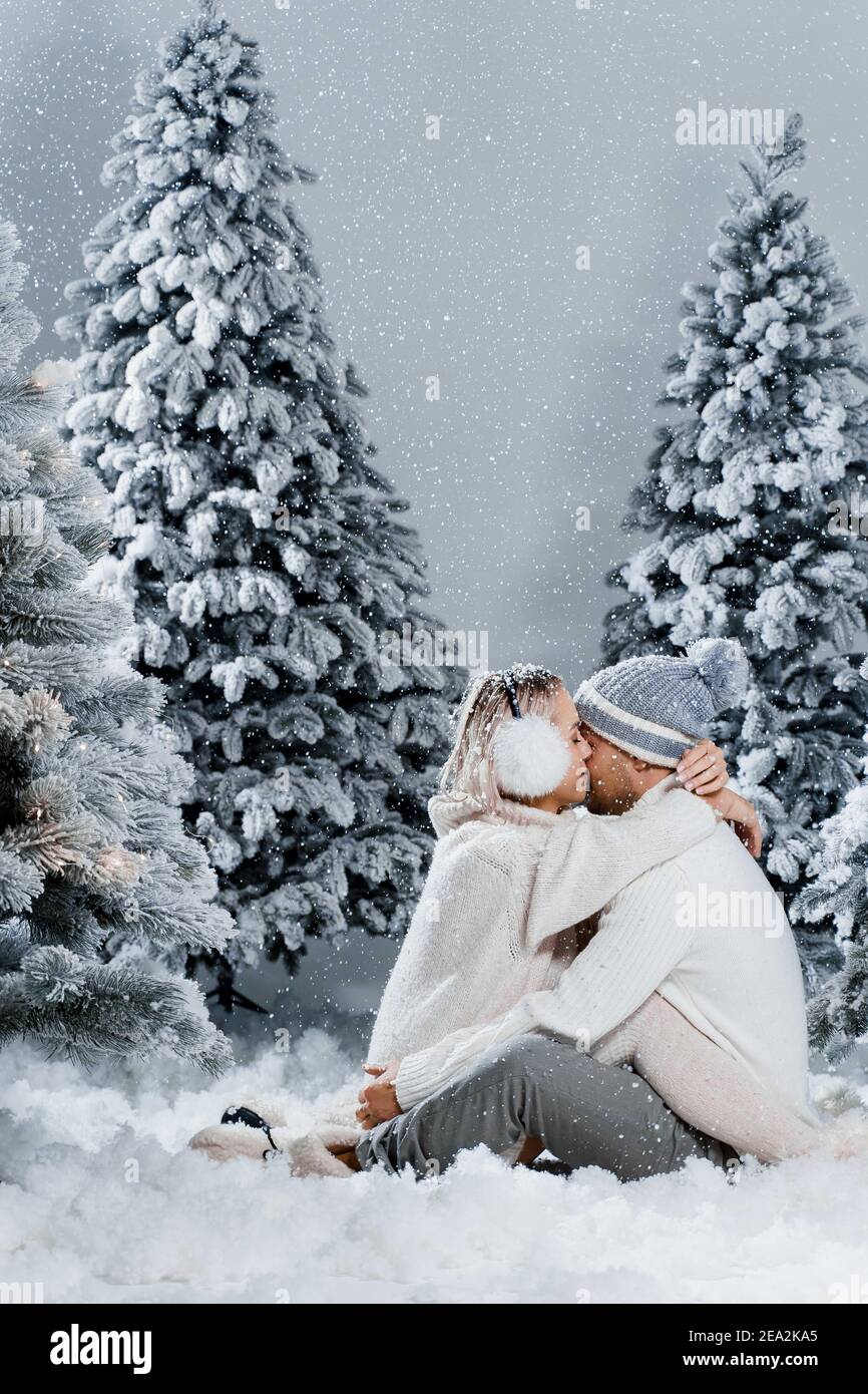 Couple seat on the snow and hug, kiss, and have fun each other. Winter ...