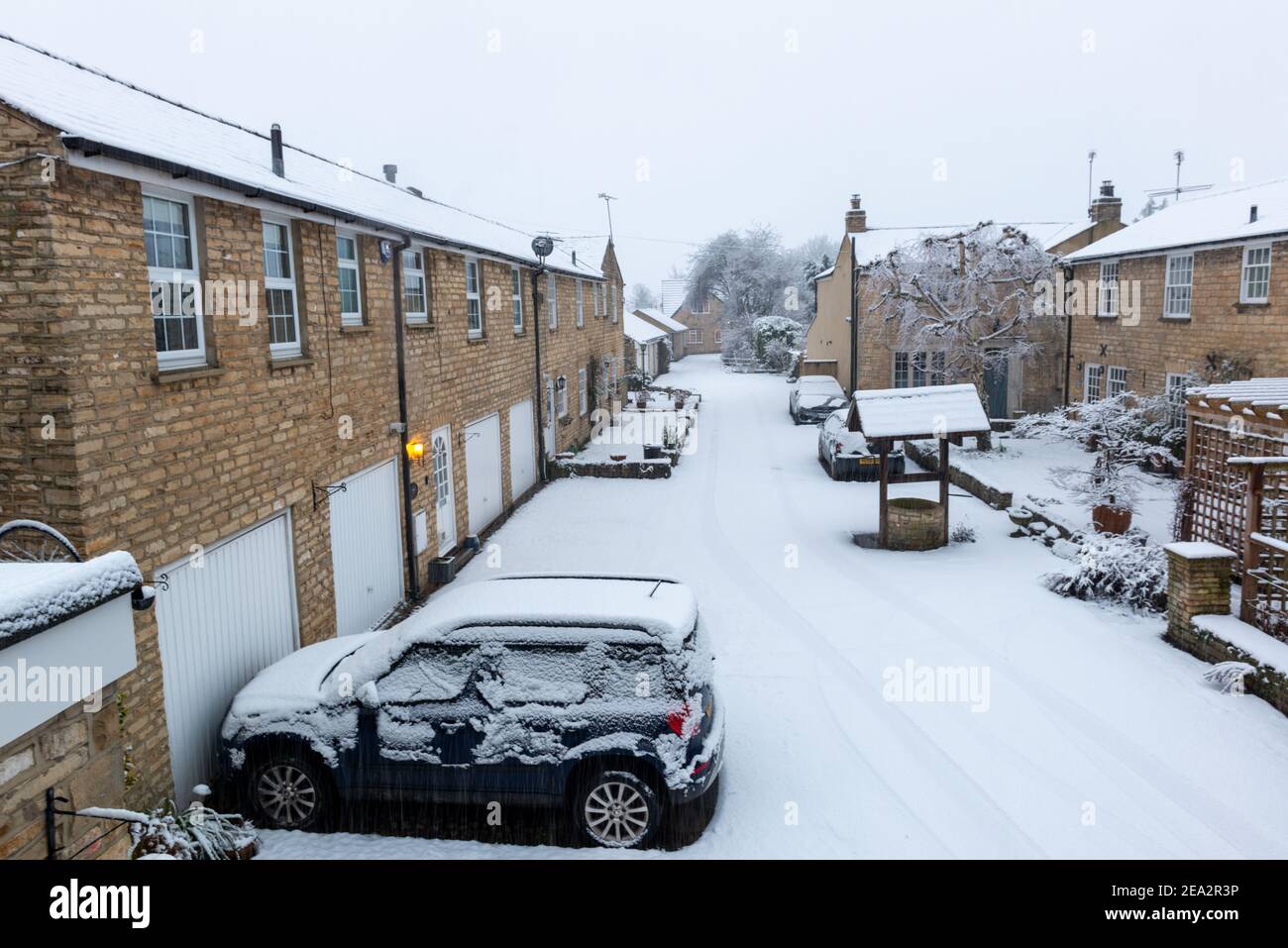 A snow covered courtyard surrounded by houses and flats with an old ...