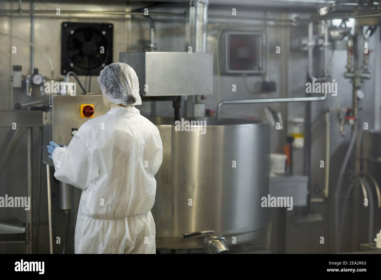 Back view portrait of young female worker operating machine units at ...