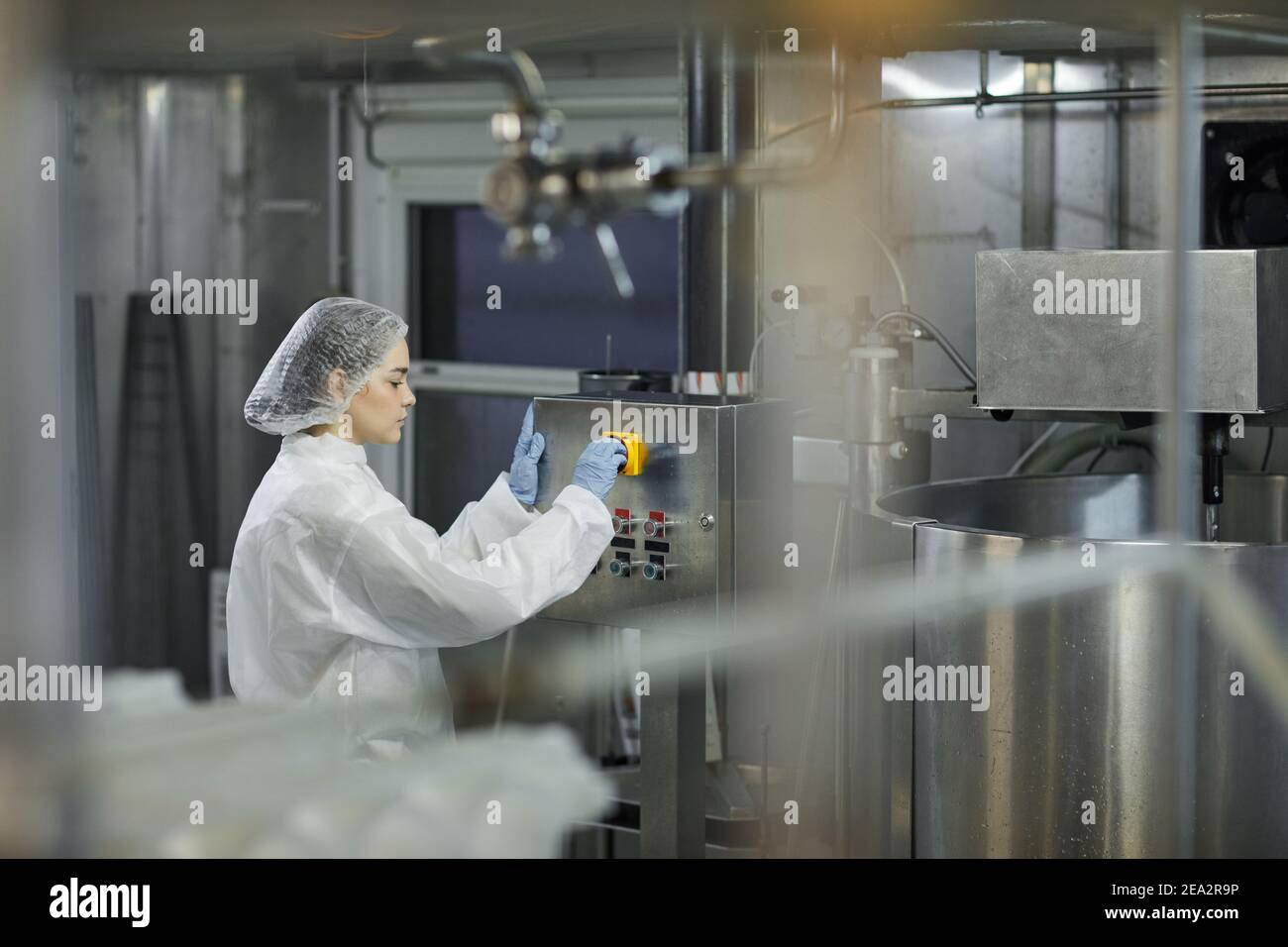 Side view portrait of female worker operating machine units at clean ...