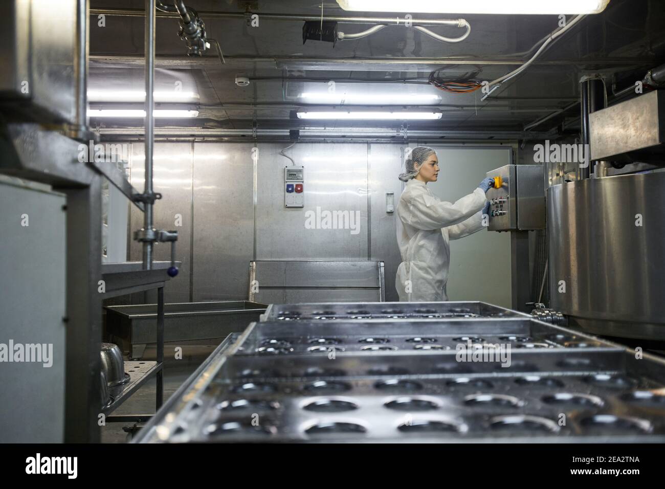 Wide angle side view at young female worker operating machine units at ...
