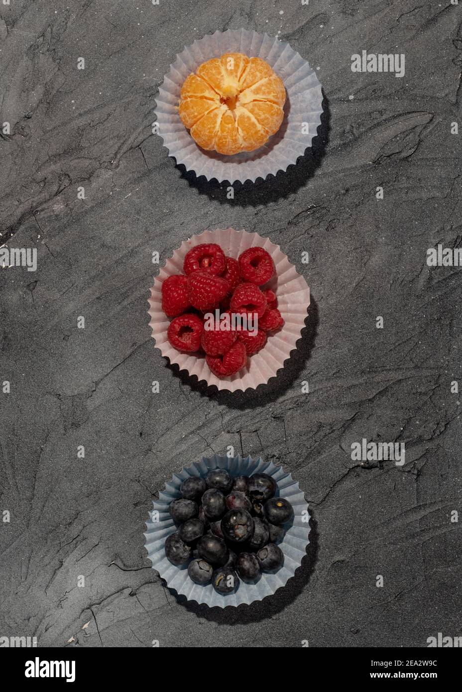 tangerine, blueberry, raspberry on grey background Stock Photo - Alamy