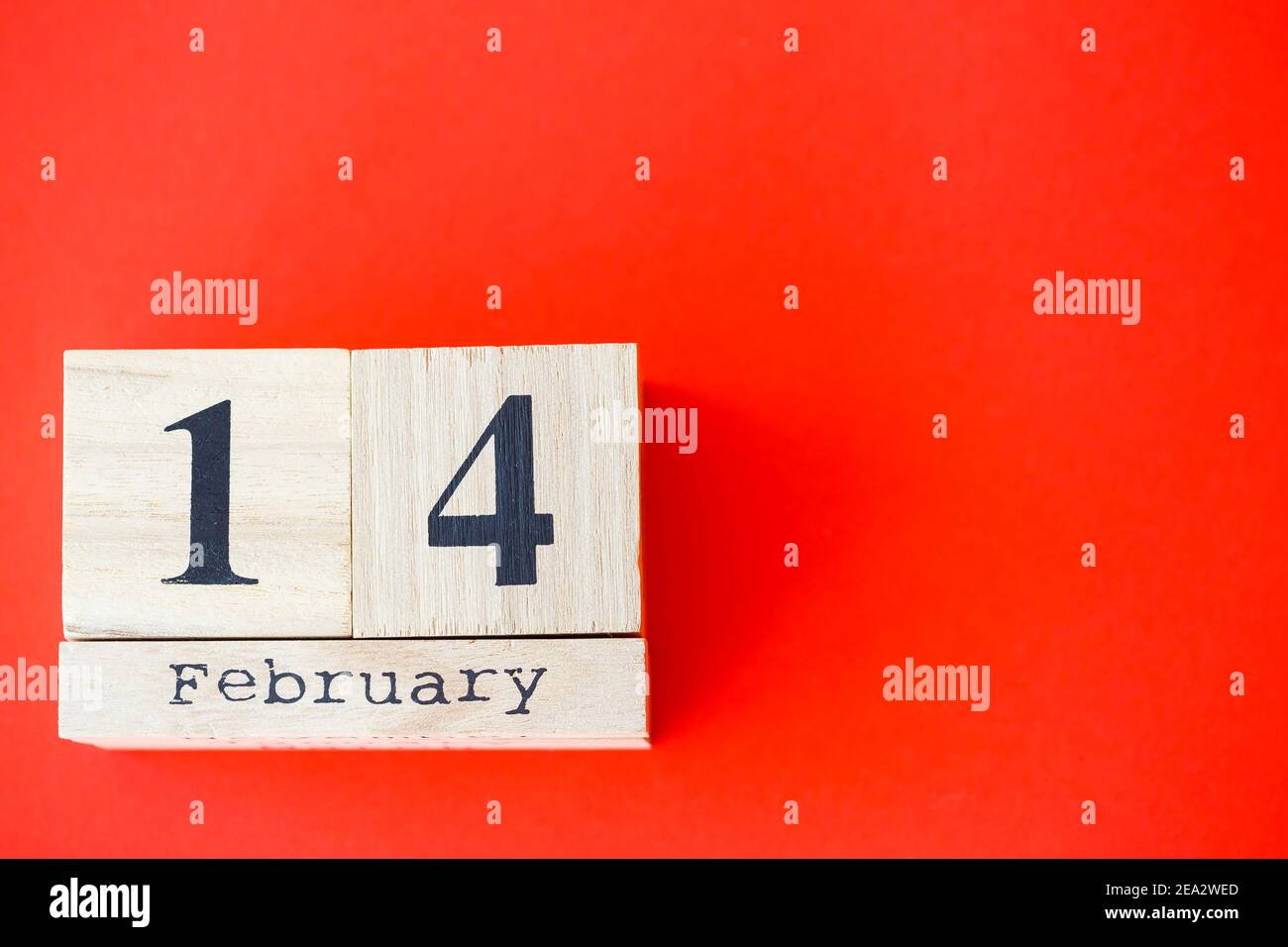 Wooden calendar with the date of February 14 on a bright red background ...