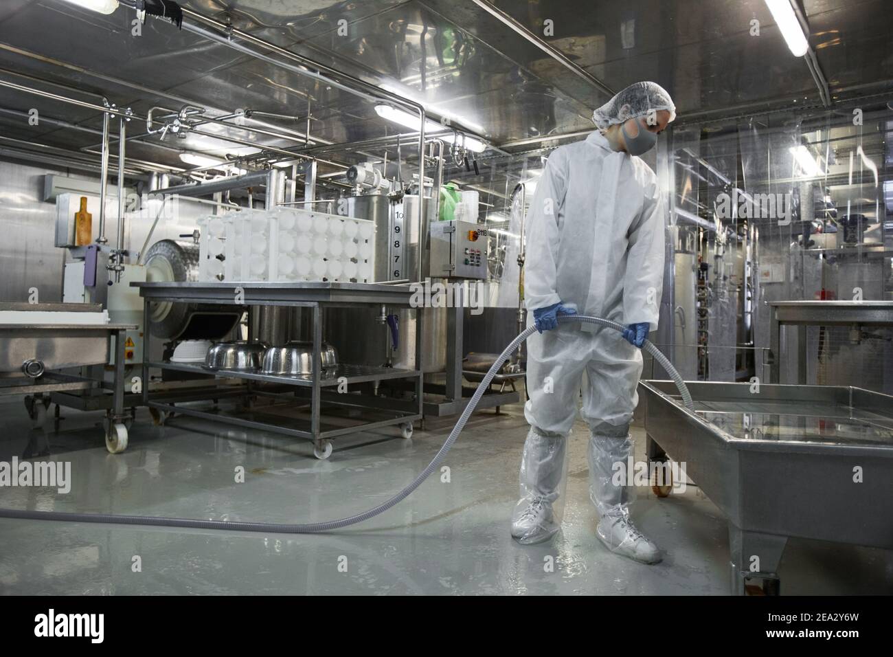 Wide angle full length portrait of female worker washing equipment at ...