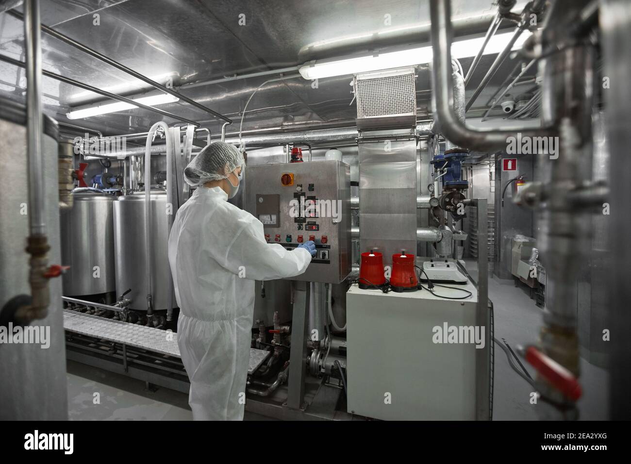 Back view portrait of female worker operating machine units at clean ...