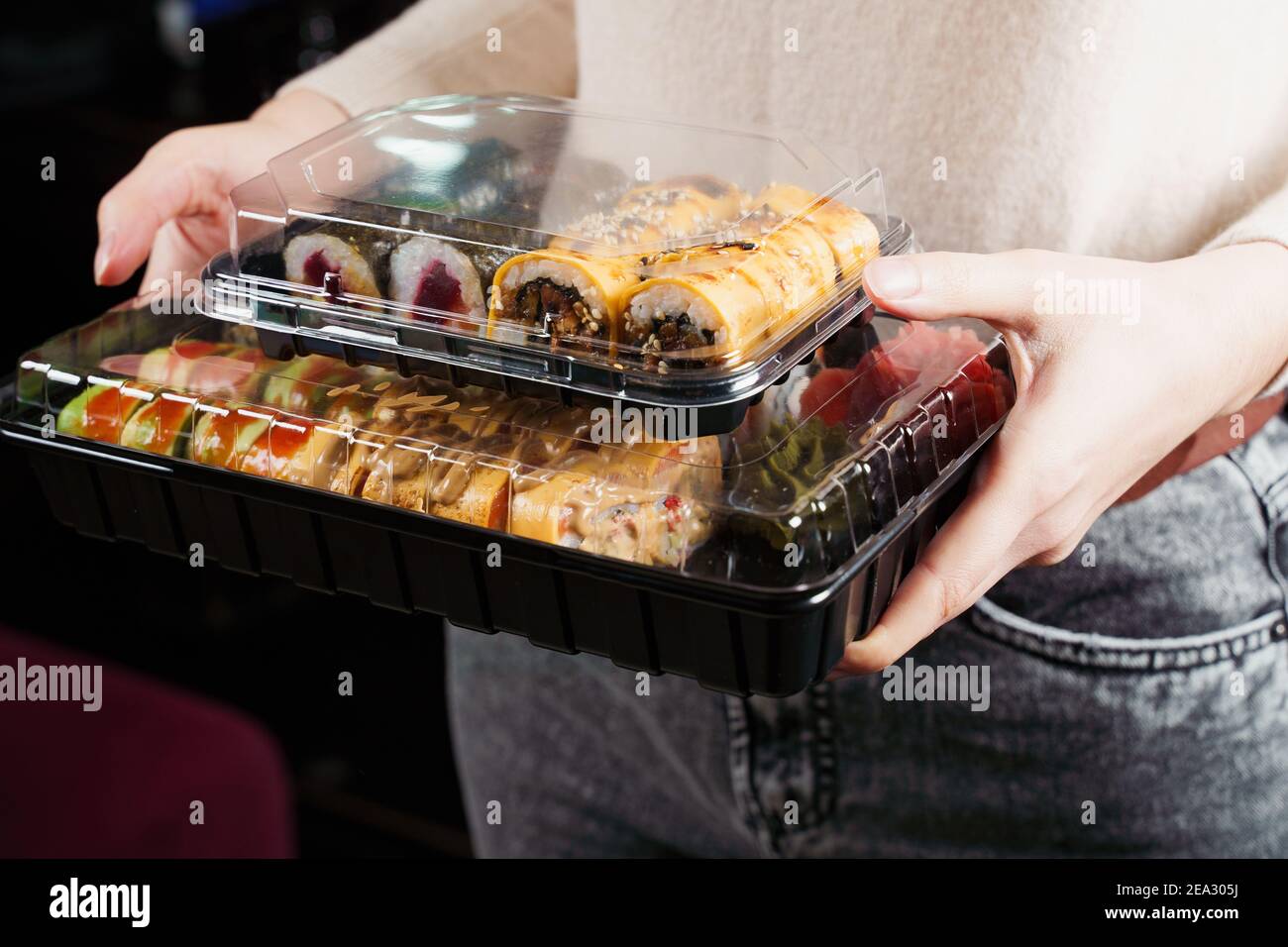Sushi roll food delivery service. Holding sushi set box on black ...