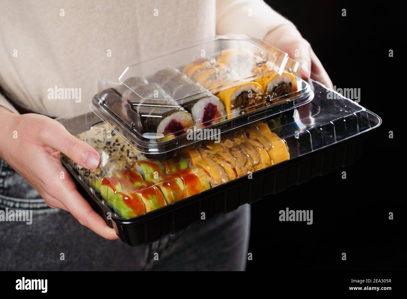 Sushi roll food delivery service. Holding sushi set box on black ...