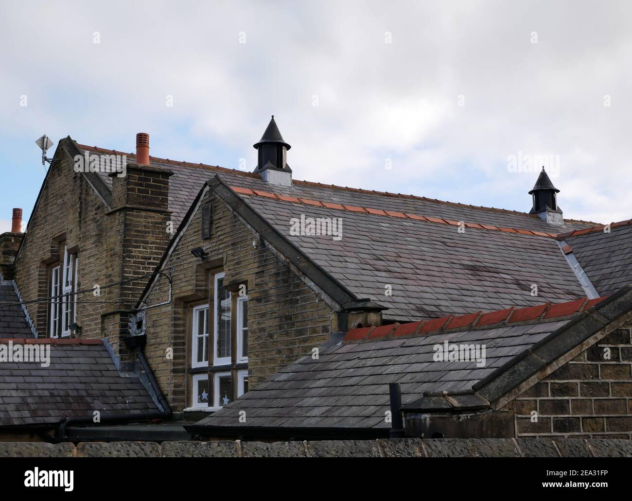Stone built building with several slate roofs terracotta capping's two ...