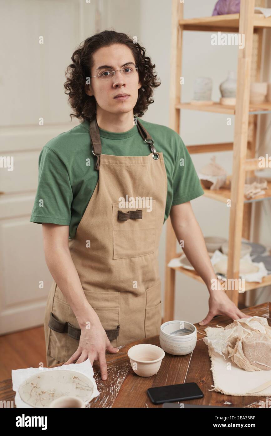 Vertical portrait of young male artisan looking at camera while ...