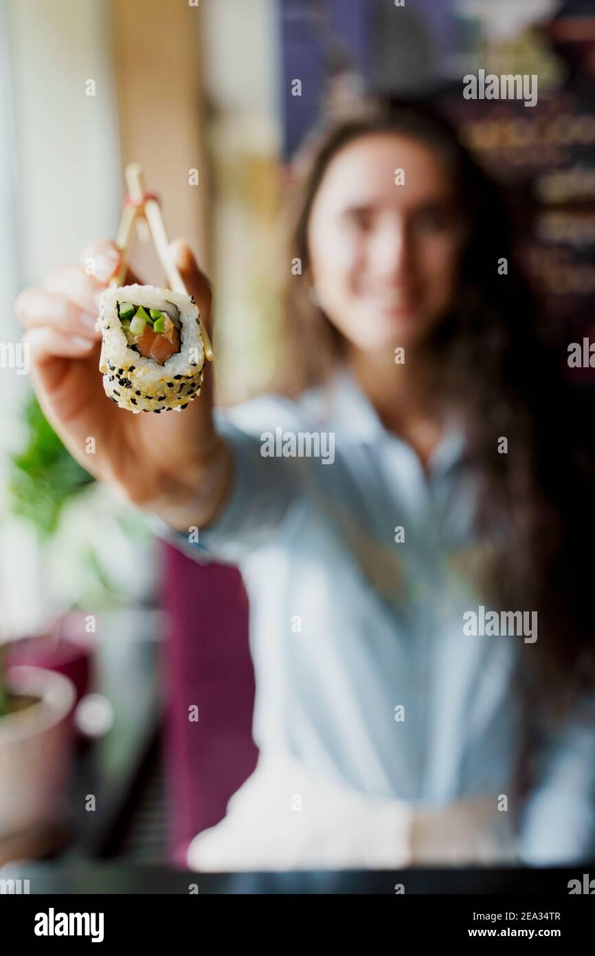 Happy girl is giving sushi to you in japanese restaurant. Young girl is ...