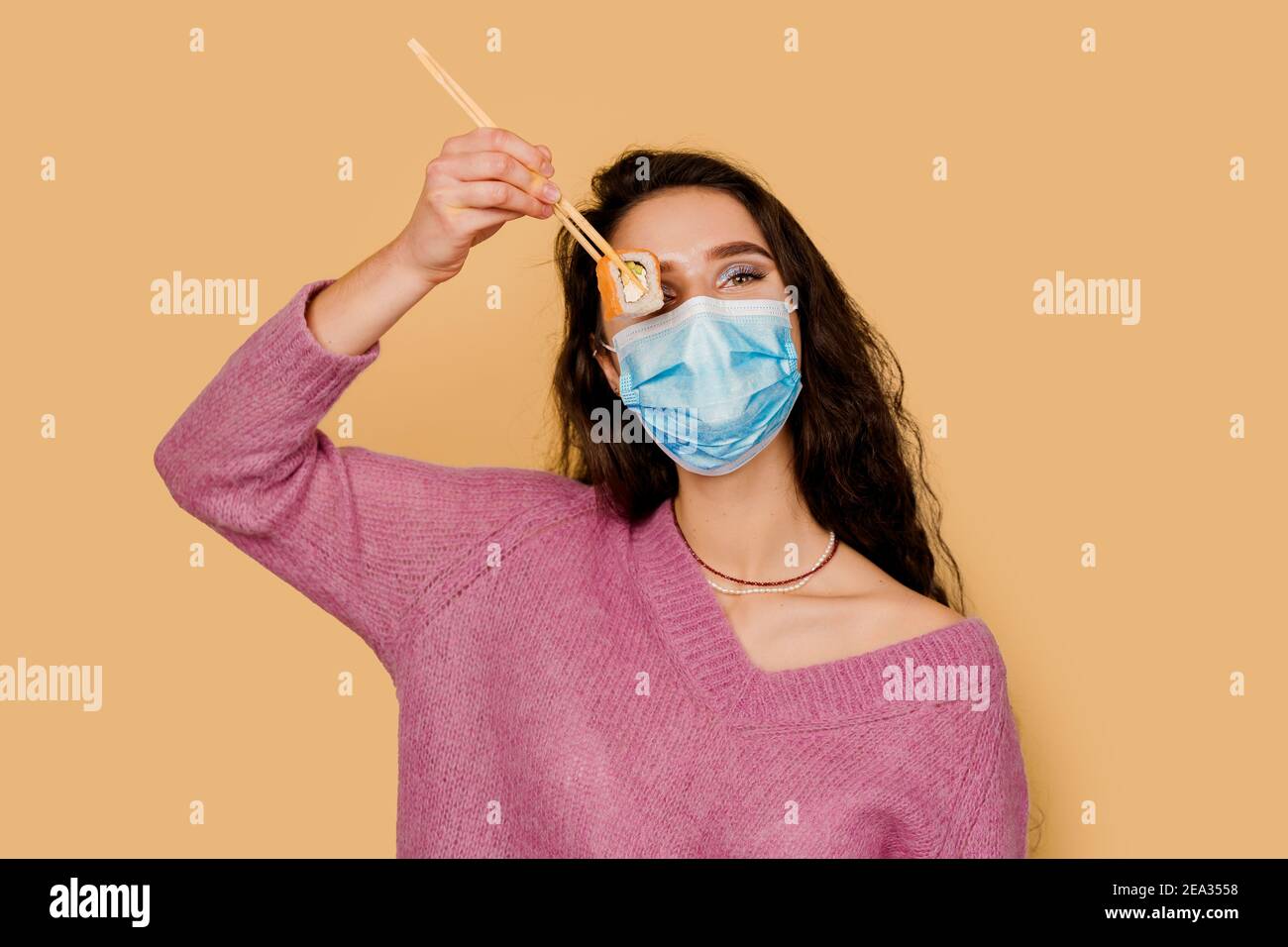Girl with sushi in medical mask isolated on yellow background. Young ...