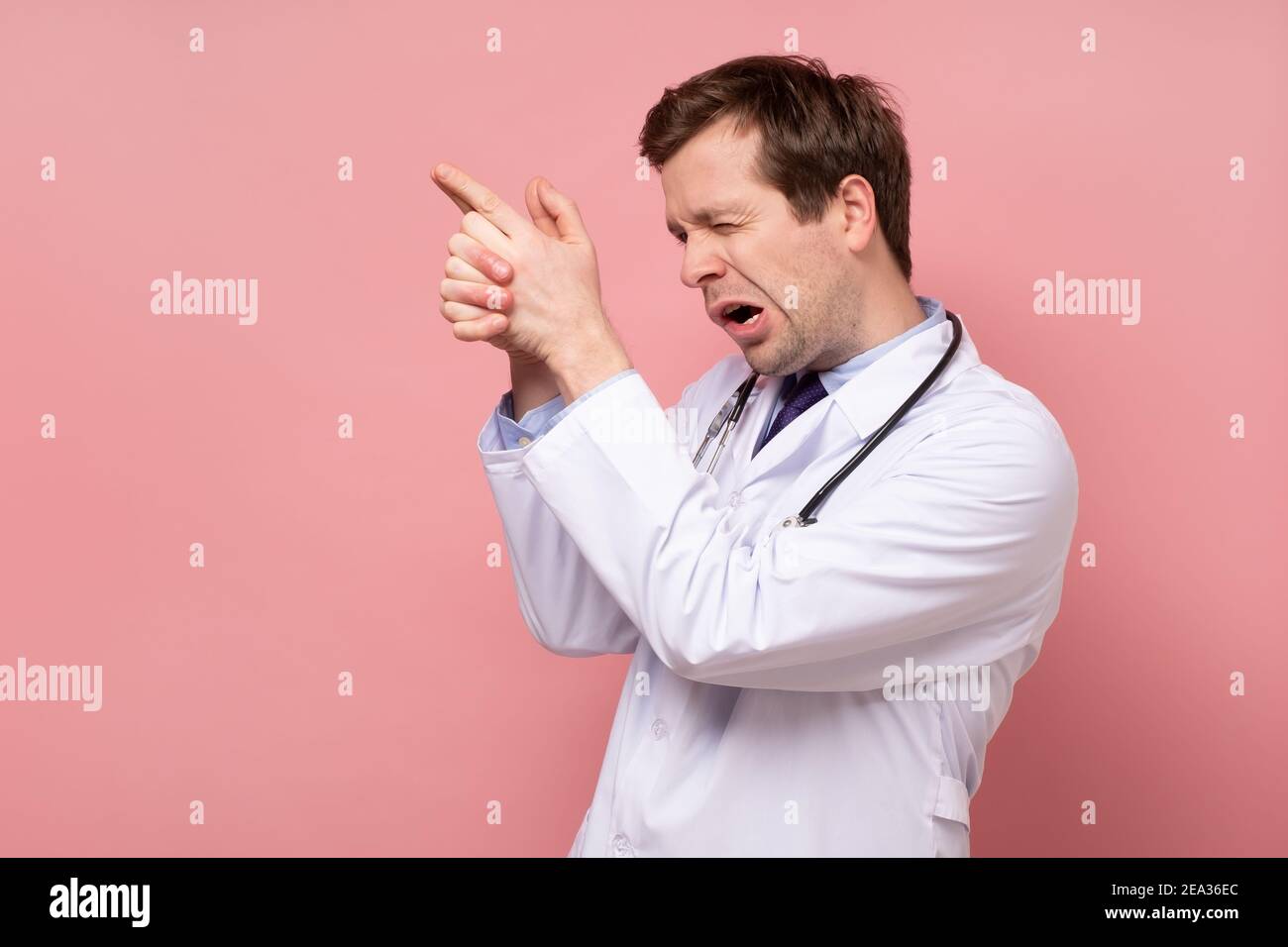 Male doctor makes a pointing finger gesture, isolated over a pink ...