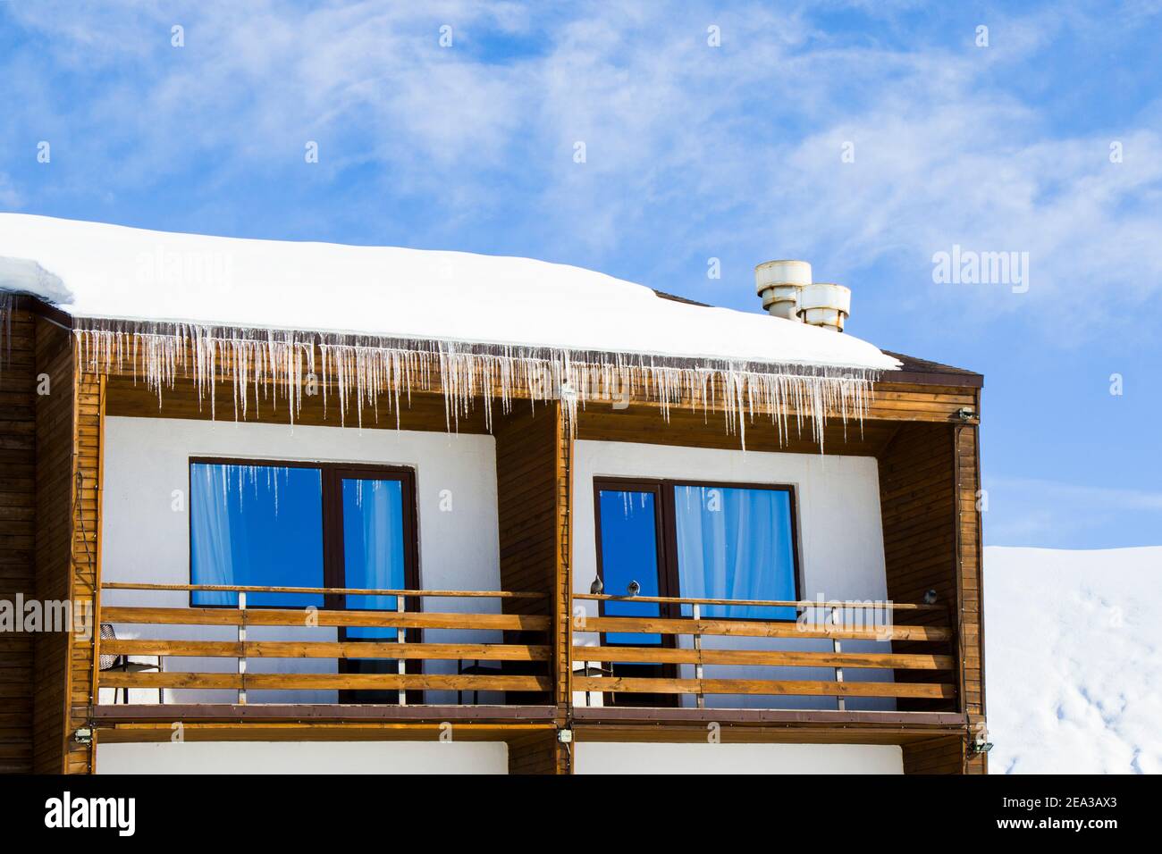 Hotel exterior in ski resort, snow, sunny day and ice. Windows and roof ...