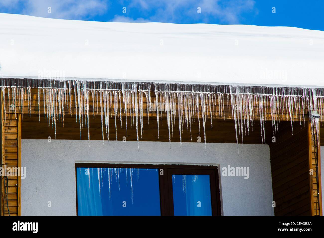 Hotel exterior in ski resort, snow, sunny day and ice. Windows and roof ...