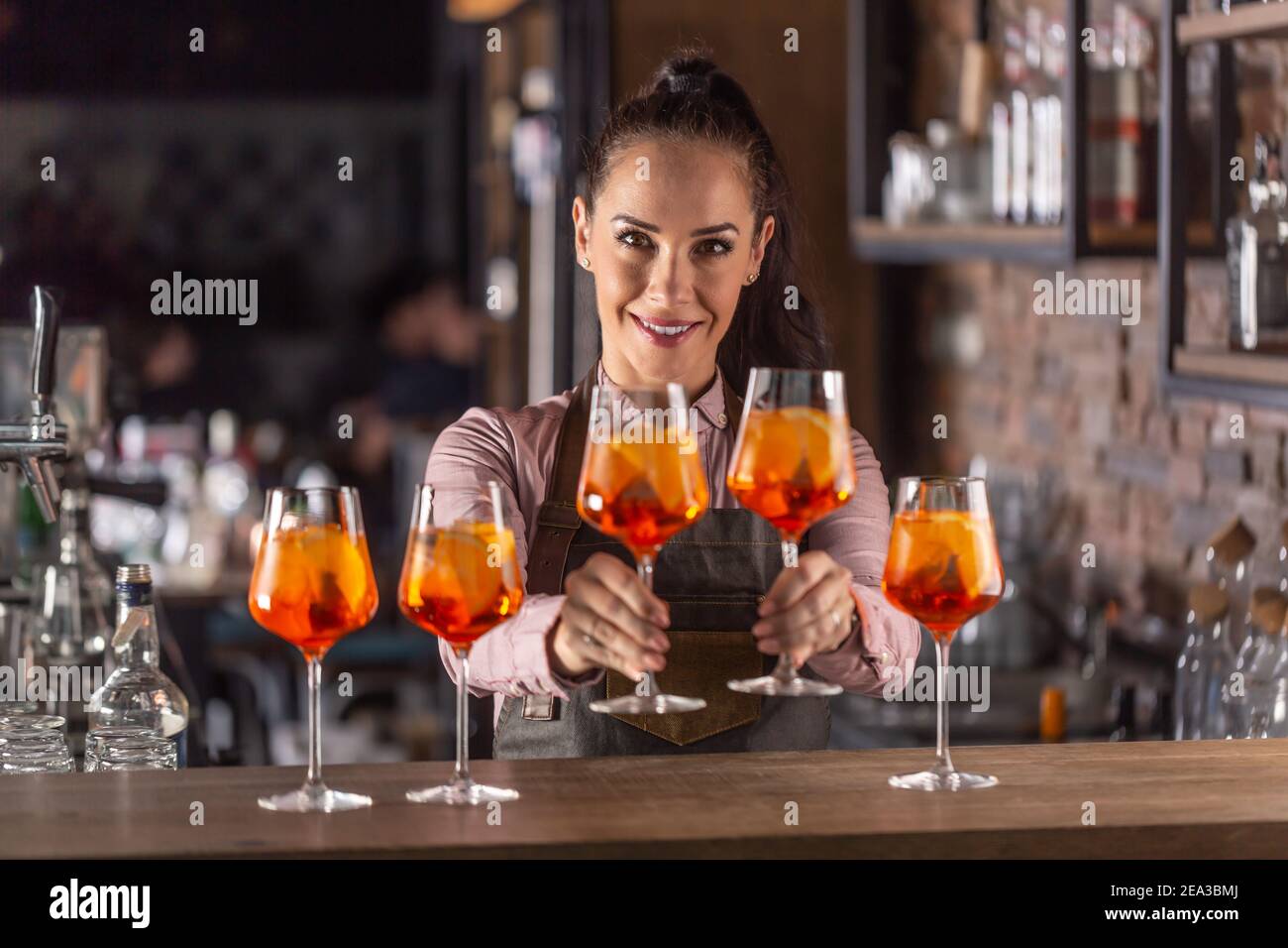 Beautiful waitress offering glasses of freshly-made aperol spritz ...