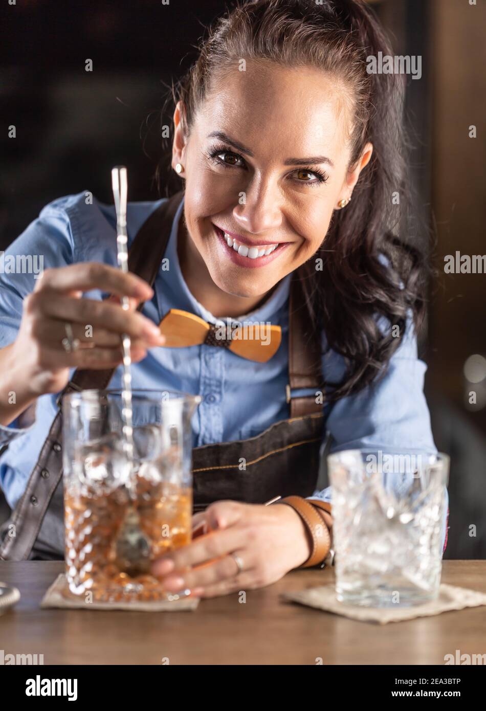 Waitress smiles while mixing old fashioned rum cocktail in a decorative ...