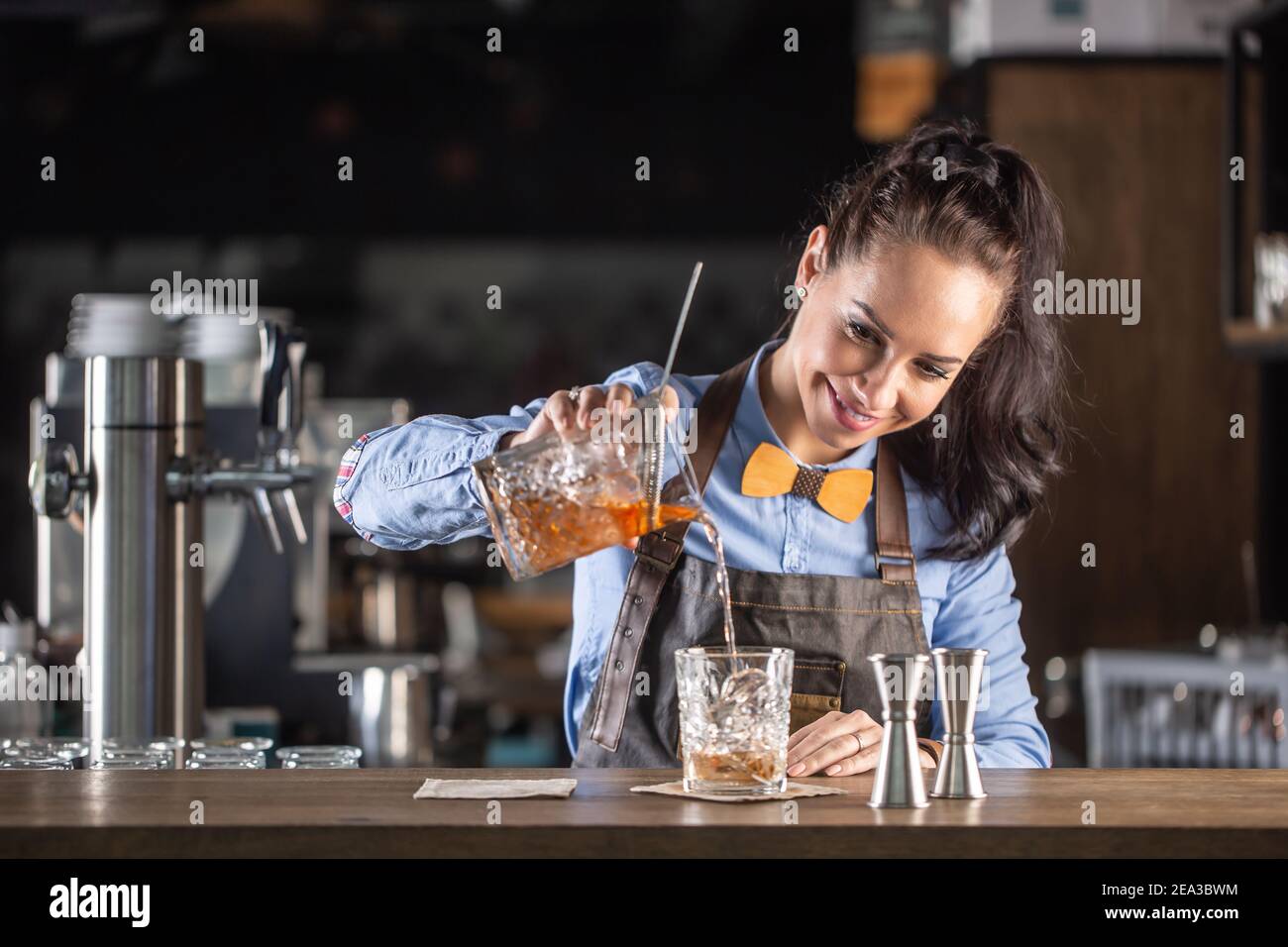 Good-looking waitress pours old fashioned whiskey cocktail into an ...