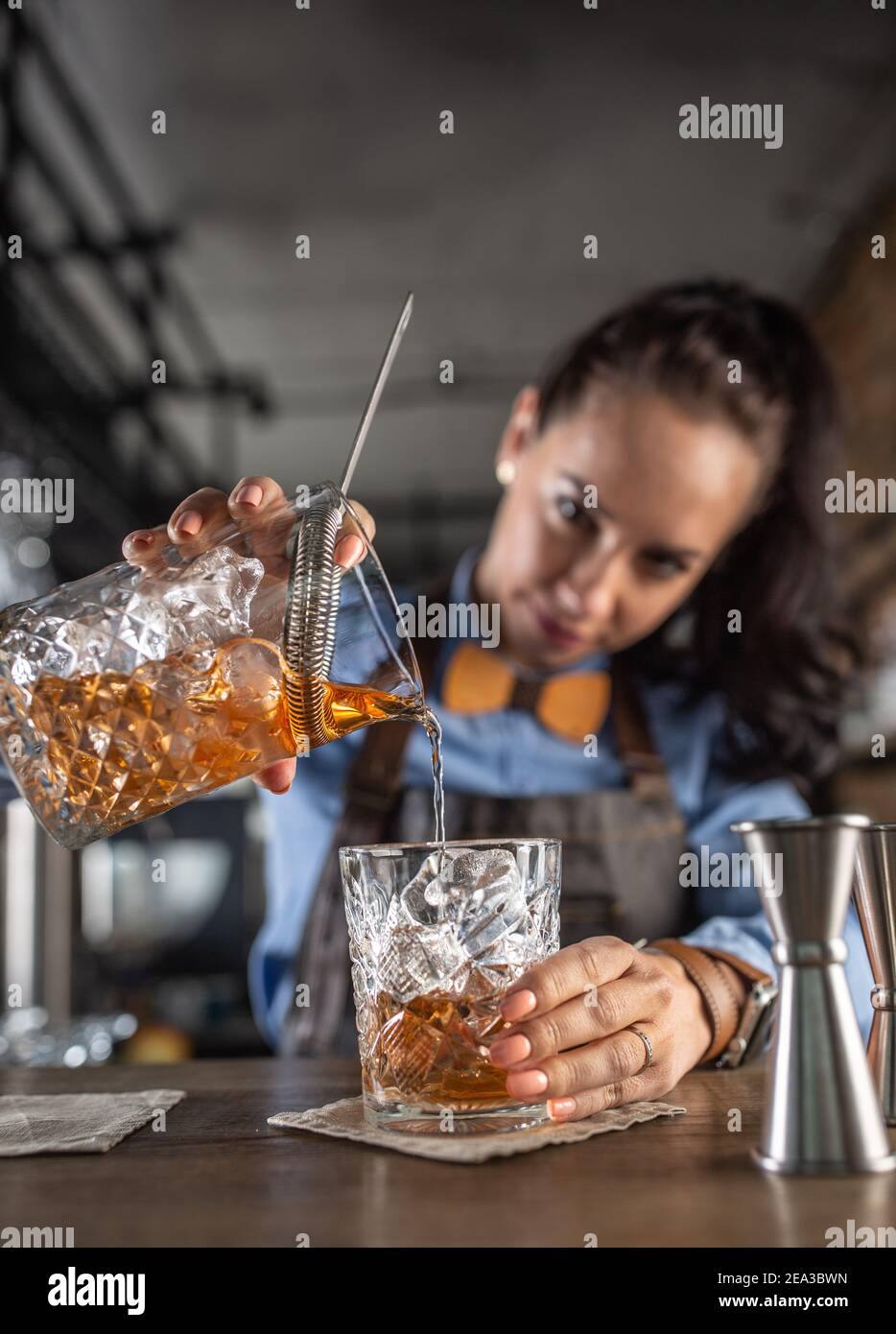 Good-looking waitress focuses on pouring old fashioned whiskey cocktail ...