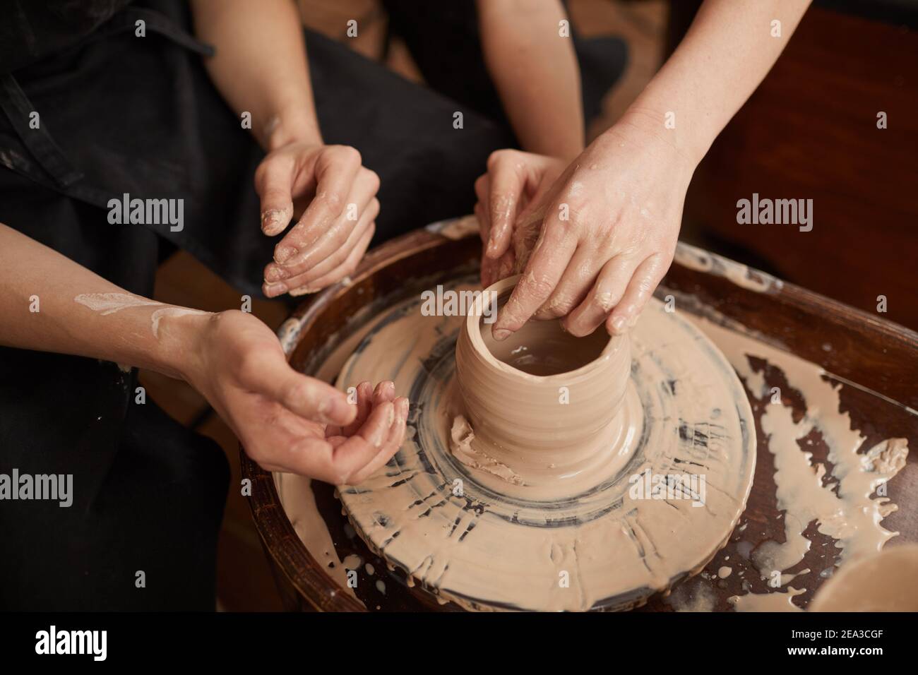 High angle close up of two people shaping clay on pottery wheel, art ...