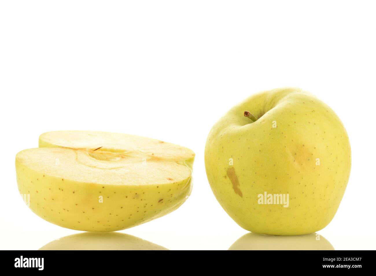 One half and one whole juicy yellow apples, close-up, on a white ...