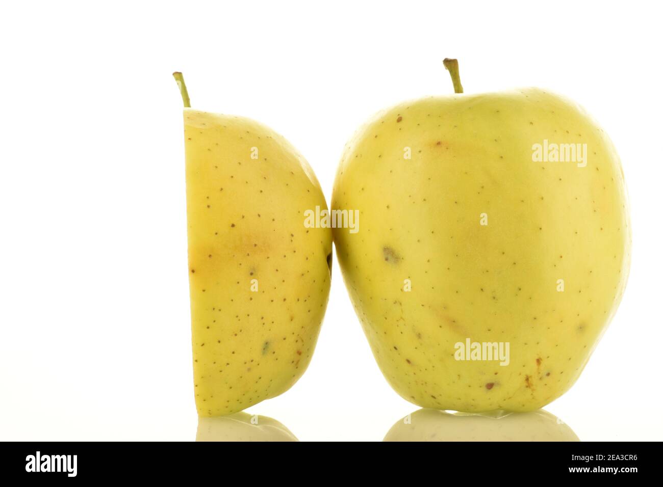 One half and one whole juicy yellow apples, close-up, on a white ...