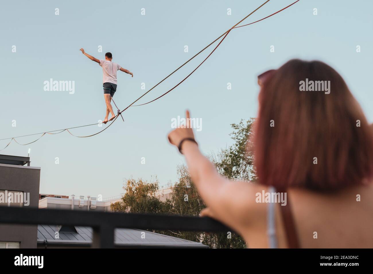 Male athlete demonstrates his skills by balancing on a narrow slackline ...