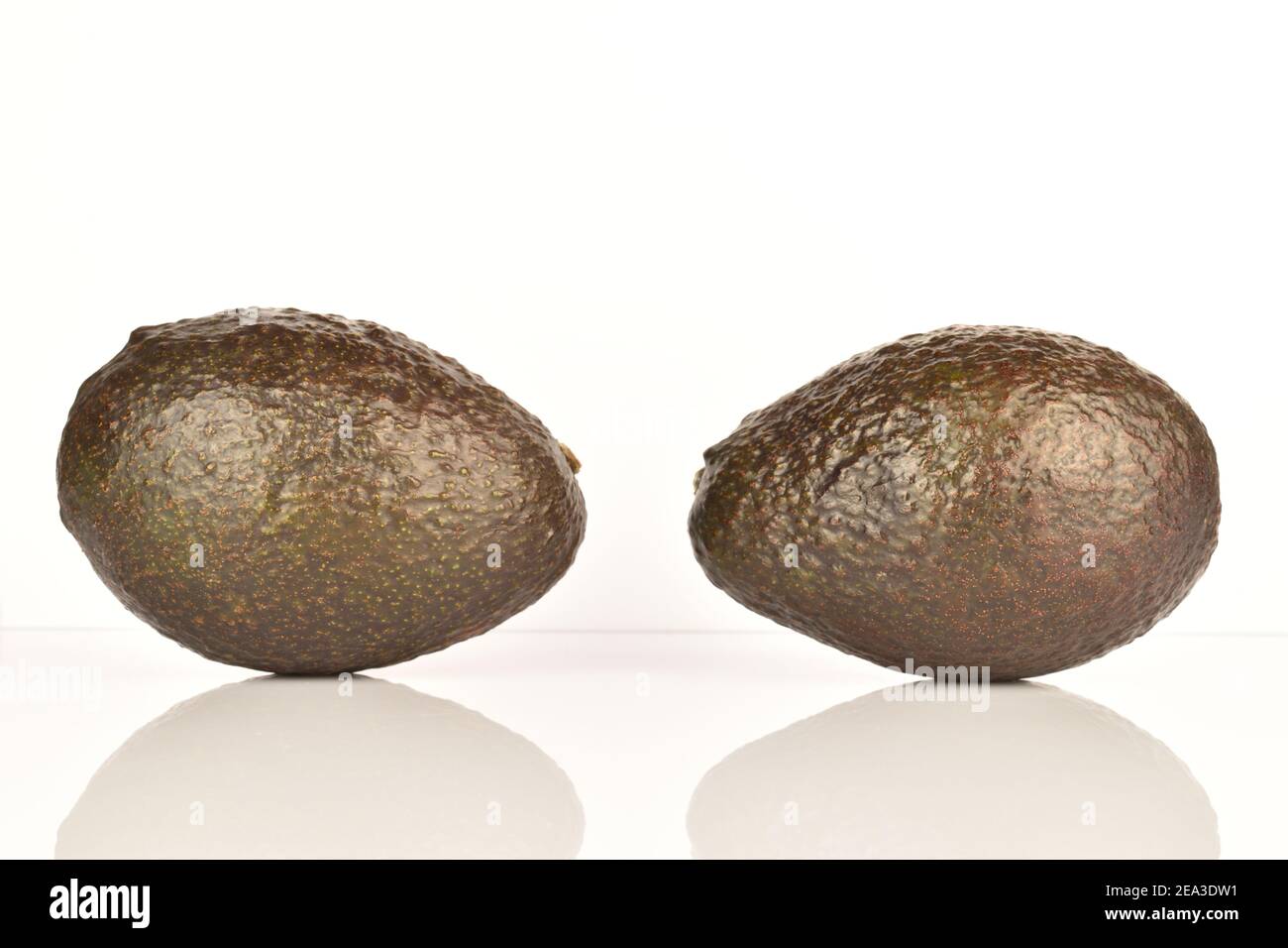 Two whole dark green rounded ripe delicious nutritious avocados on a ...