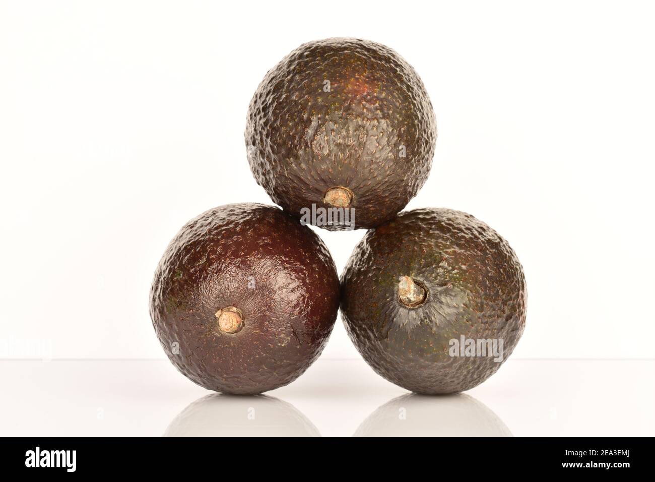 Three whole dark green rounded ripe delicious nutritious avocados on a ...