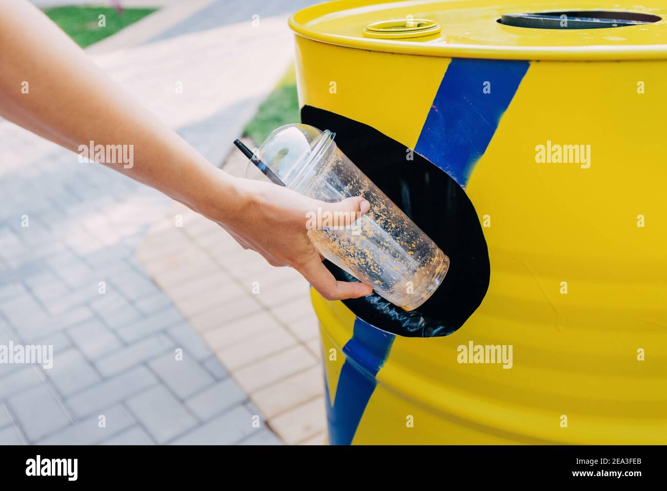 woman throws a used plastic Cup into a dumpster. Concept of waste ...