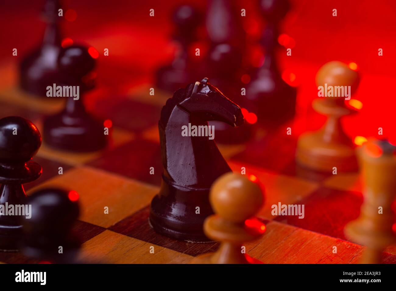 Chess fight, chess pieces on the board, toned in red. Battle fire and ...