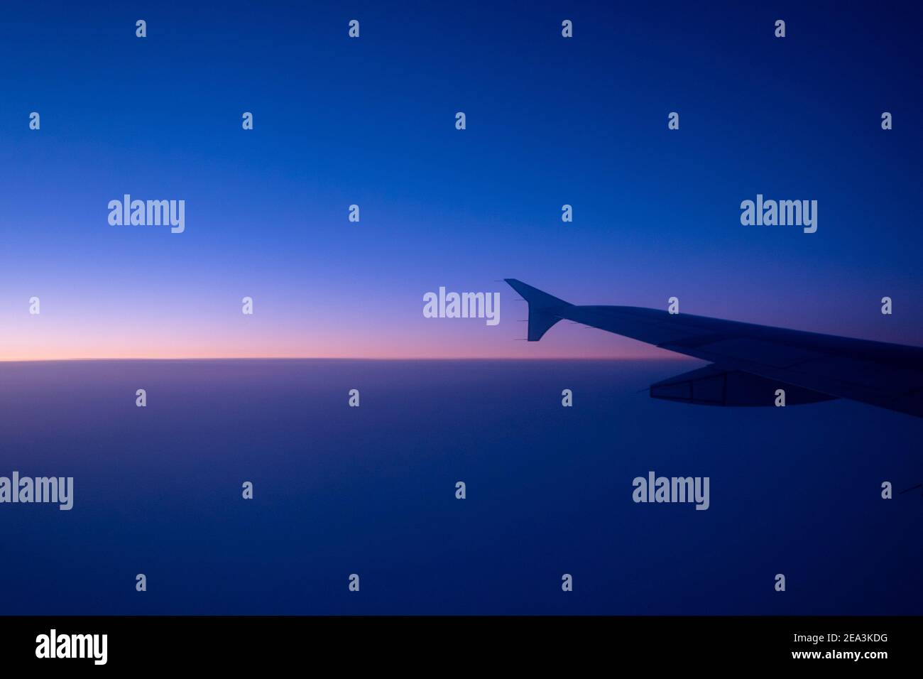 The left side wing of a large white commercial airplane flying over the ...