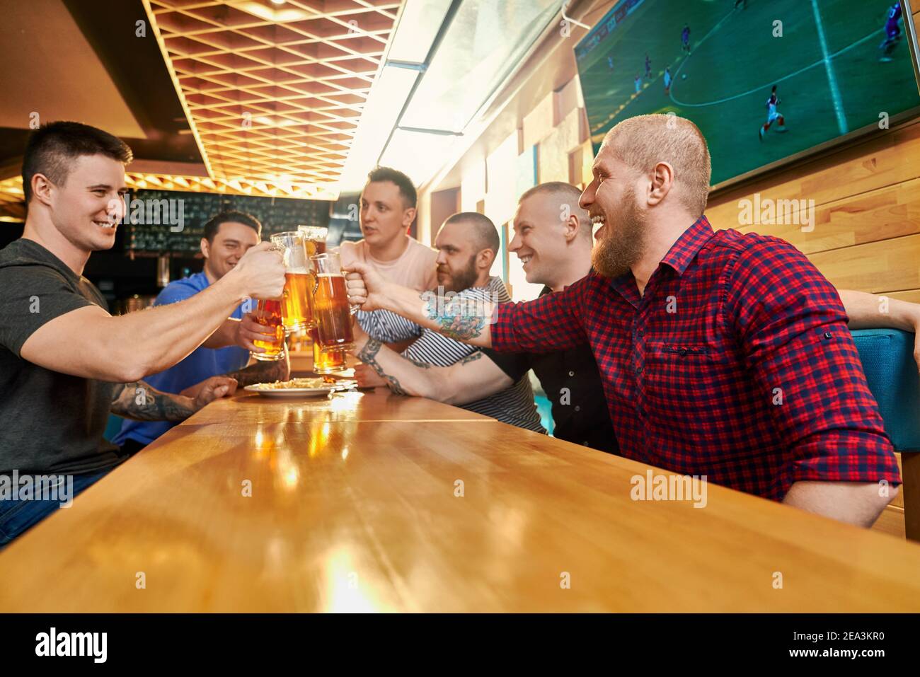 View from side of cheerful male company resting together in pub on ...