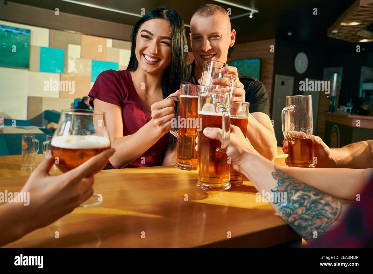 Front view of cheerful pair sitting at table in bar and laughing with ...