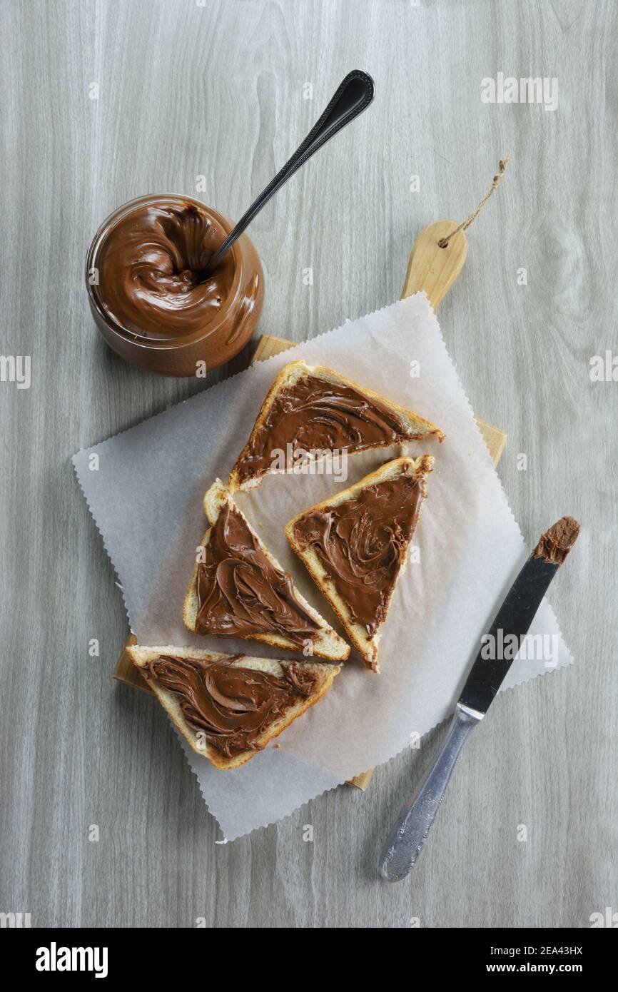 Slice of bread spread with hazelnut praline paste on a plate and grey ...